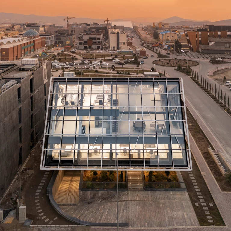 Glazed office rises out of the ground with a dramatic tilting form