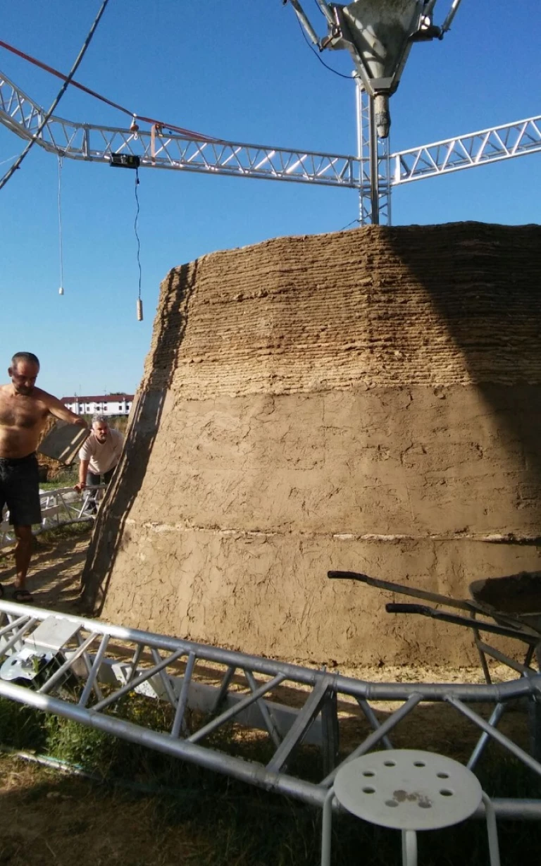 Low-cost 3D-printed shelter being built from clay and straw